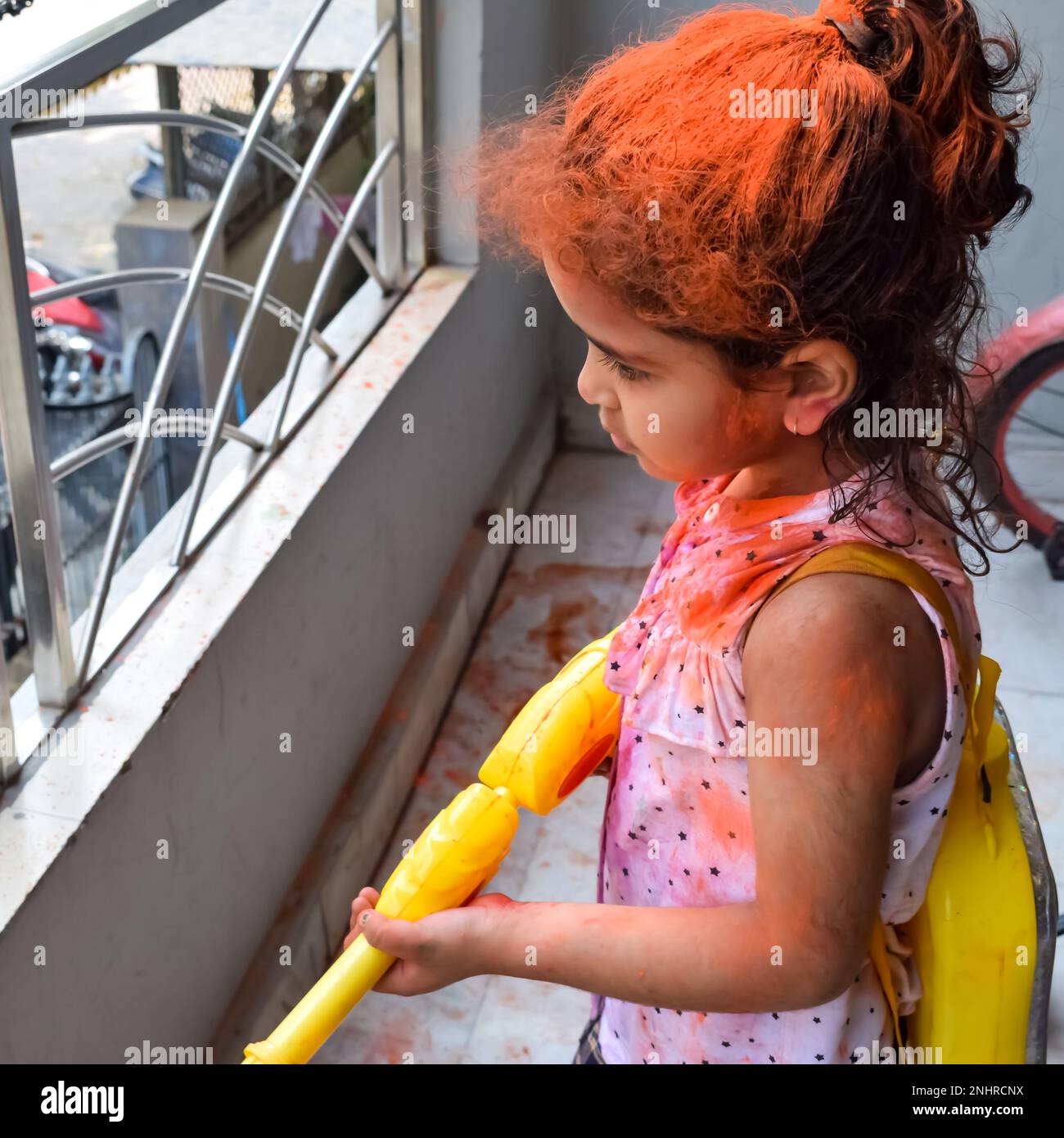 Sweet little Indian girl playing colours on Holi festival, holding ...