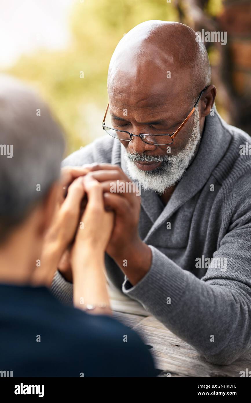 Praying with his wife. a senior couple holding hands in prayer while ...