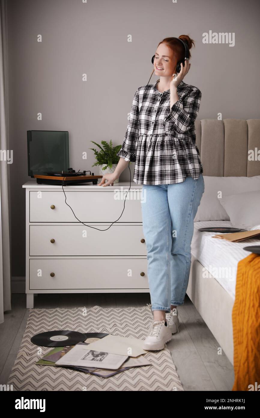 Young woman listening to music with turntable in bedroom Stock Photo ...