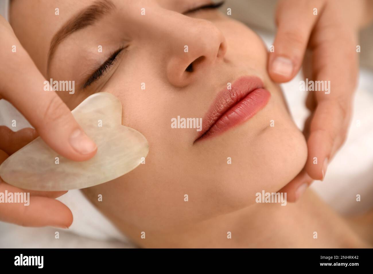 Young woman receiving facial massage with gua sha tool in beauty salon, closeup Stock Photo - Alamy