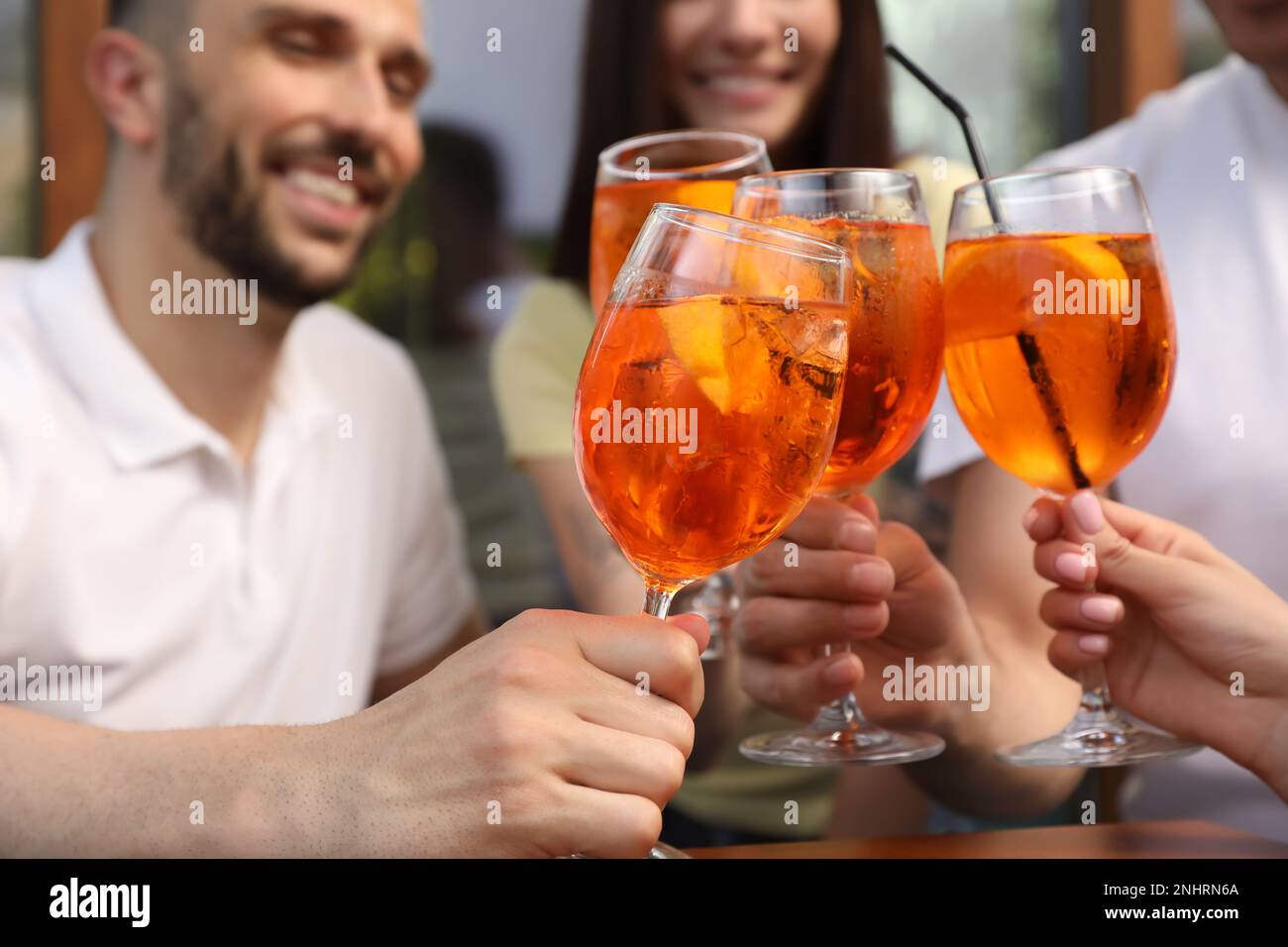 Friends clinking glasses of Aperol spritz cocktails outdoors, closeup ...