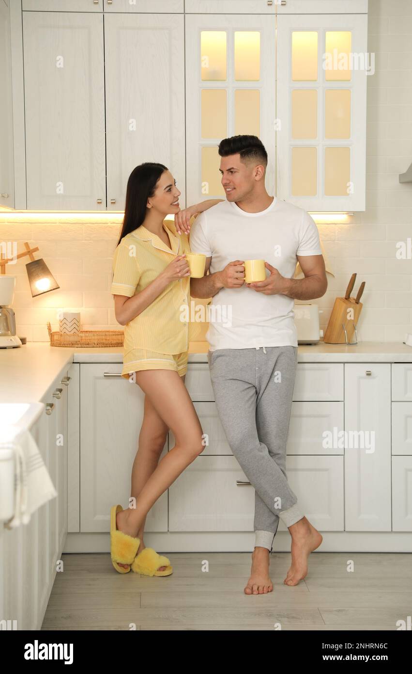 Happy couple wearing pyjamas with cups of coffee in kitchen Stock Photo ...