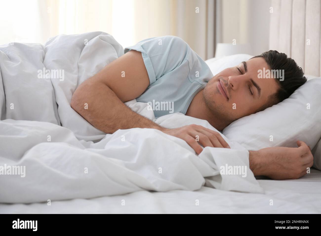 Man sleeping in bed with white linens at home Stock Photo - Alamy