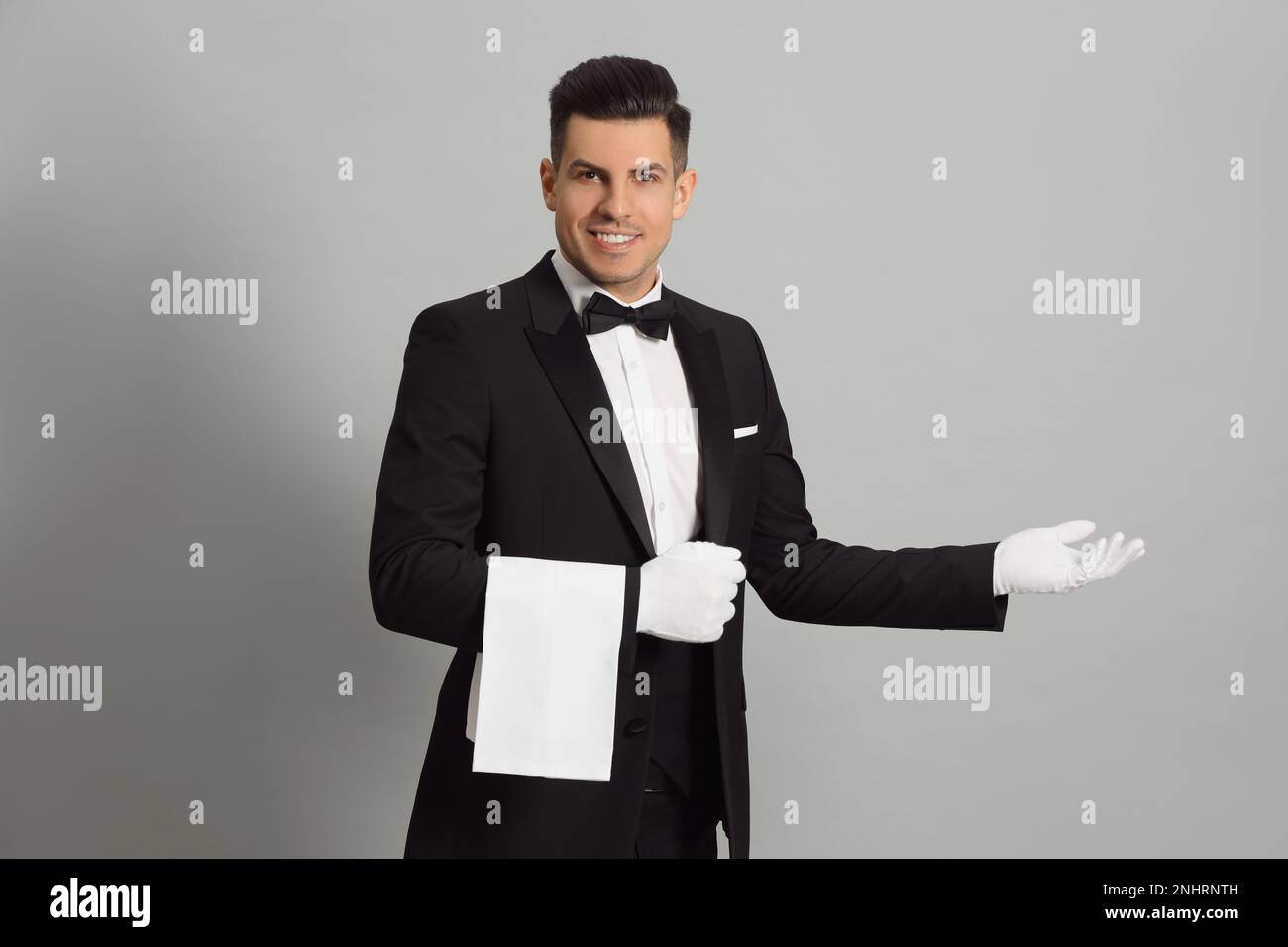 Handsome butler with towel on grey background Stock Photo - Alamy