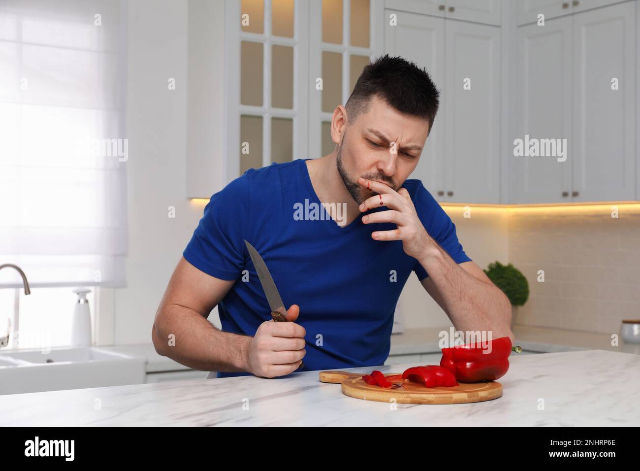 Man cut finger with knife while cooking at white marble table in ...