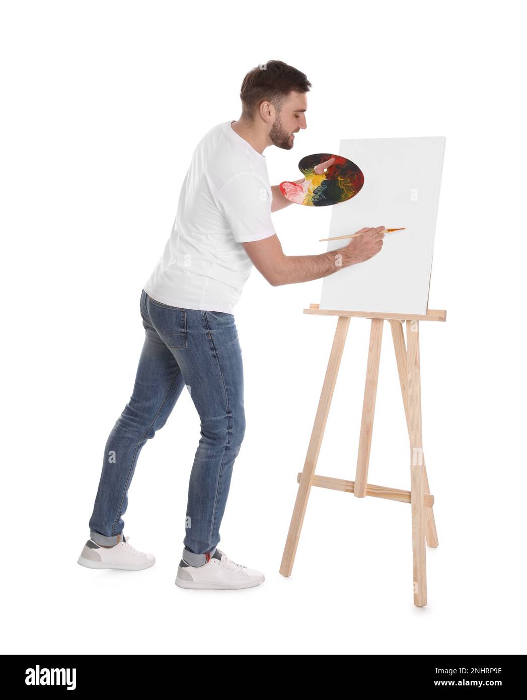 Man painting with brush on easel against white background. Young artist ...