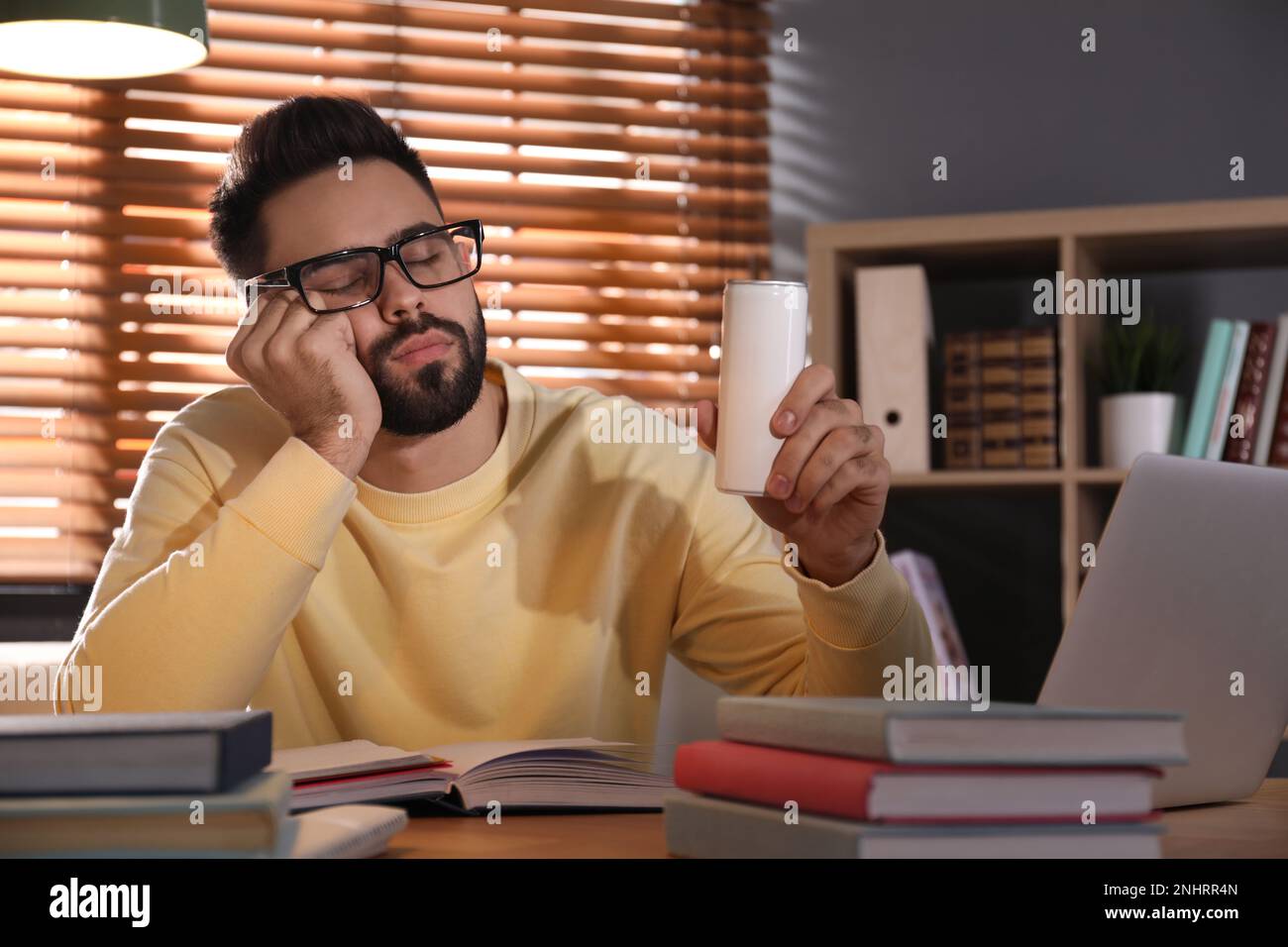 Tired young man with energy drink studying at home Stock Photo - Alamy