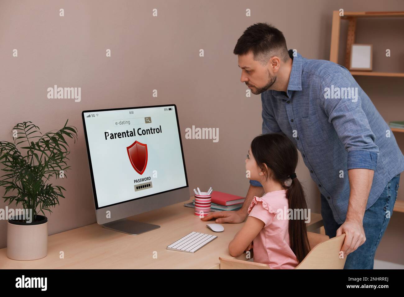 Dad installing parental control on computer at table indoors. Child ...