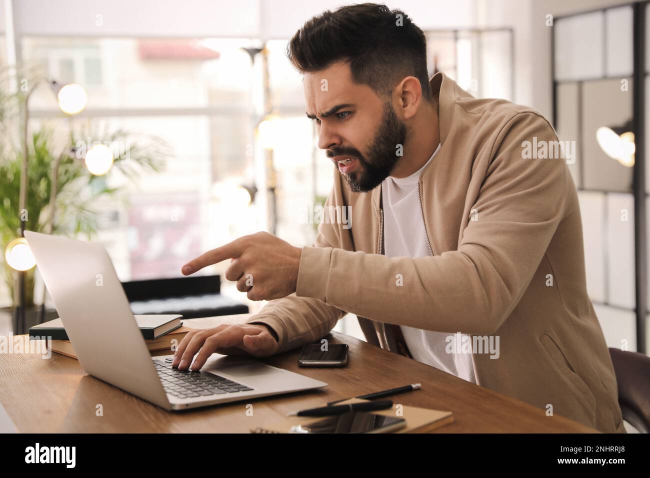 Emotional young man working on laptop in office. Online hate concept ...