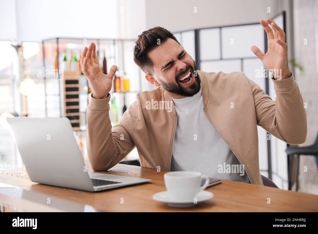 Emotional young man working on laptop in office. Online hate concept ...