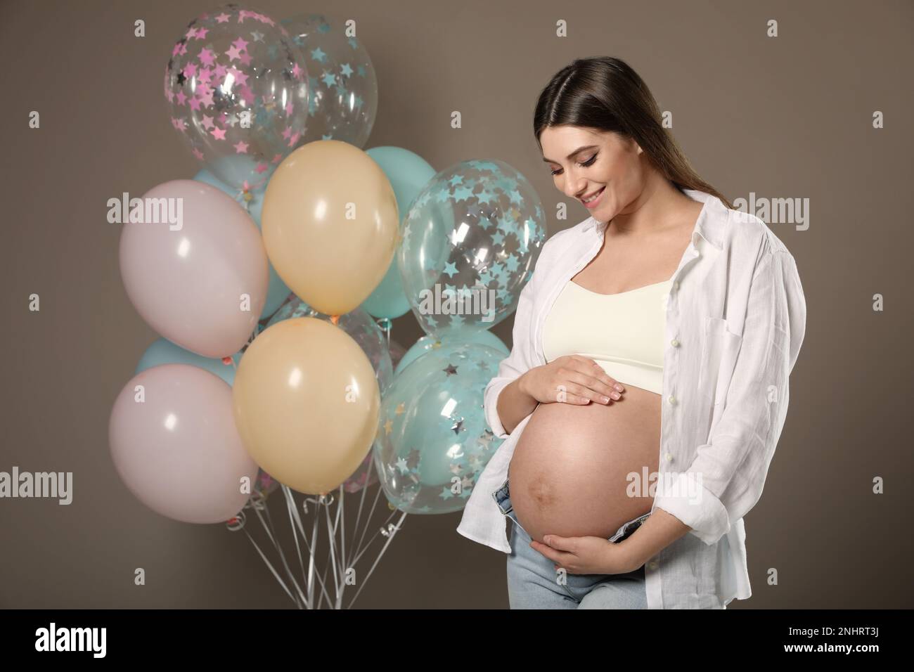 Happy pregnant woman with balloons near dark wall. Baby shower party ...