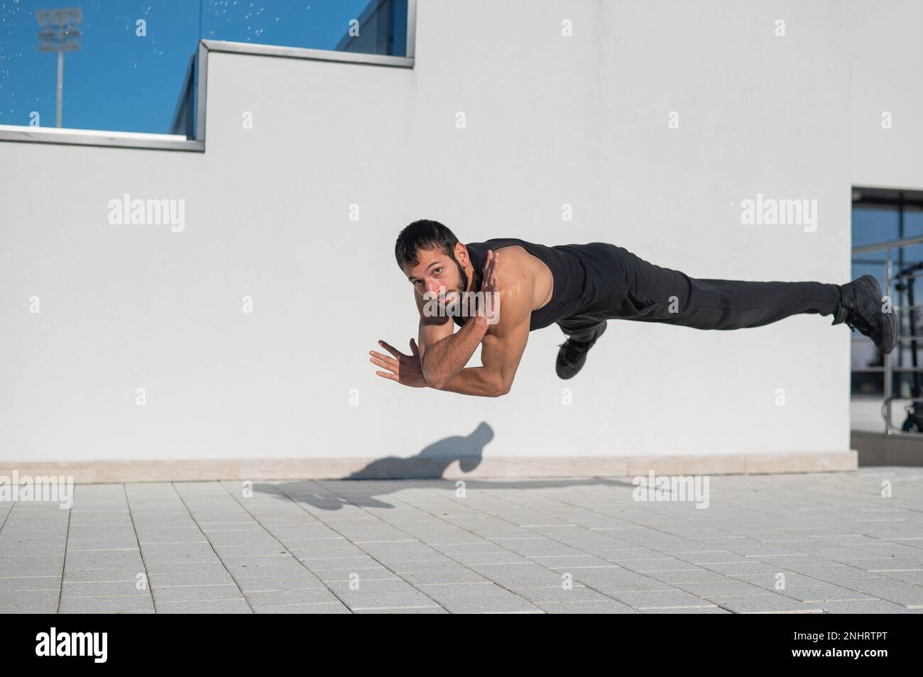 A man in black sportswear jumps while doing push-ups outdoors Stock ...