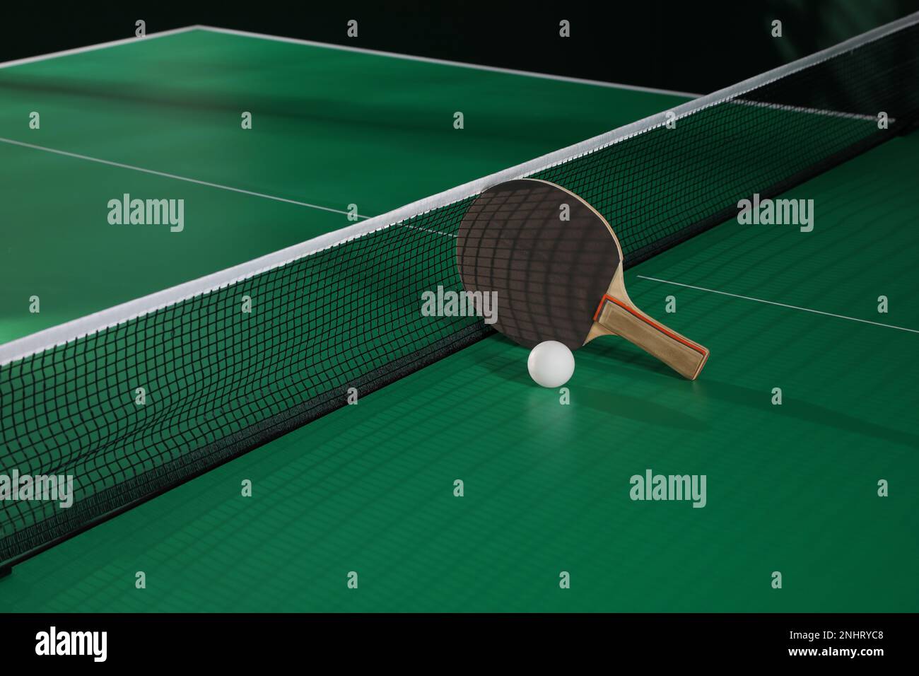 Black racket and ball on green ping pong table indoors Stock Photo - Alamy