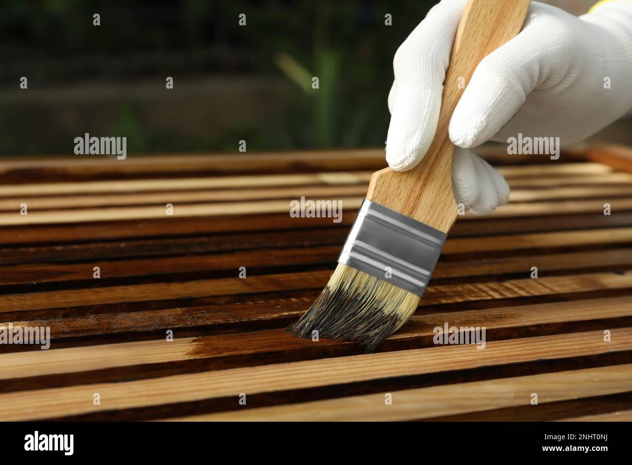 Worker applying wood stain onto planks outdoors, closeup Stock Photo ...