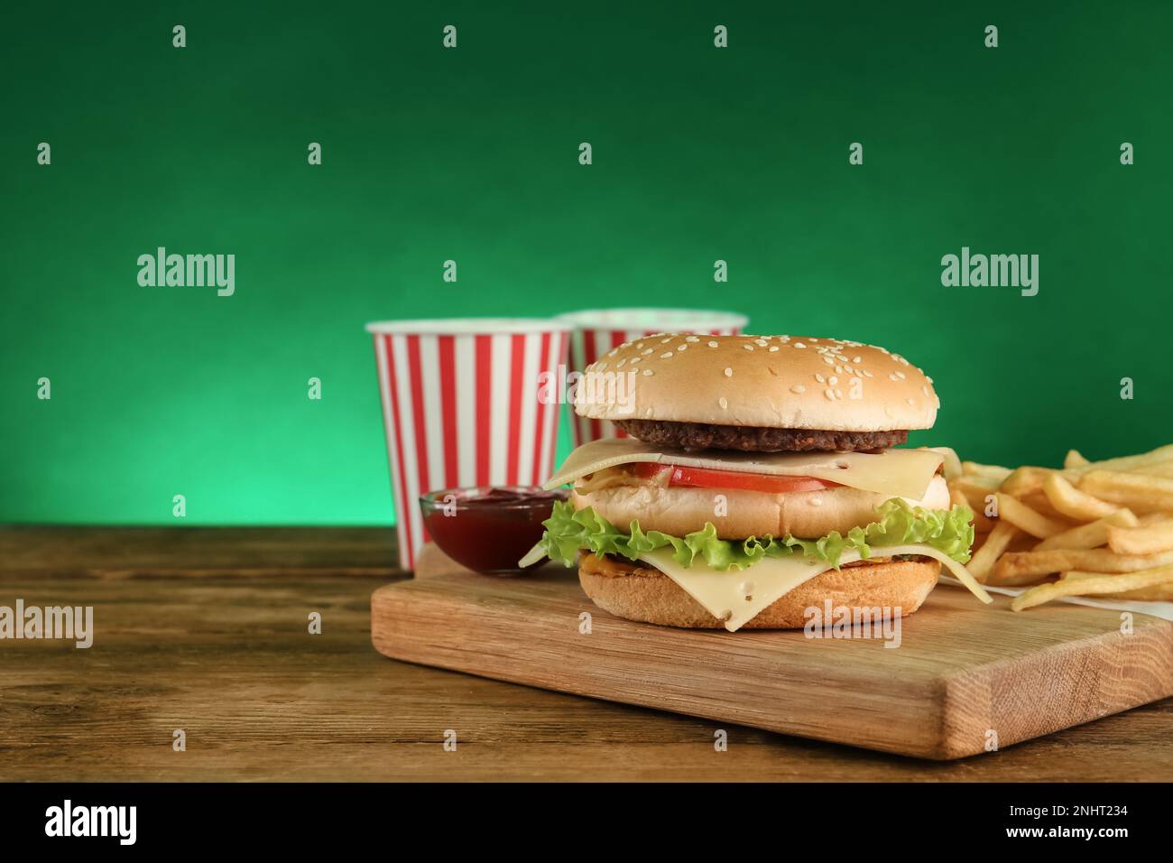 Delicious fast food menu on wooden table against green background ...