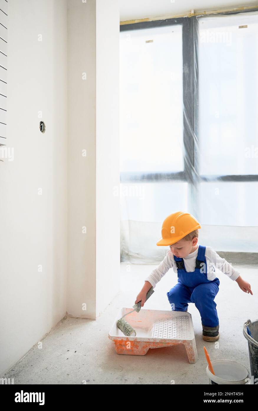 Boy construction worker painting wall with paint brush in apartment ...
