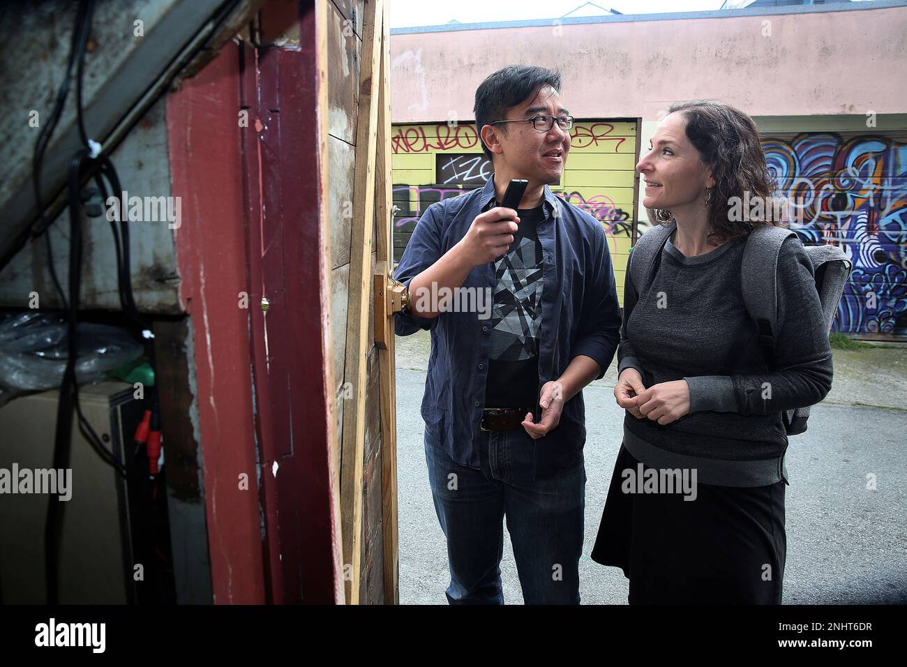 Curator Sarah Klein (right) and David Kwan (middle) work on changing ...