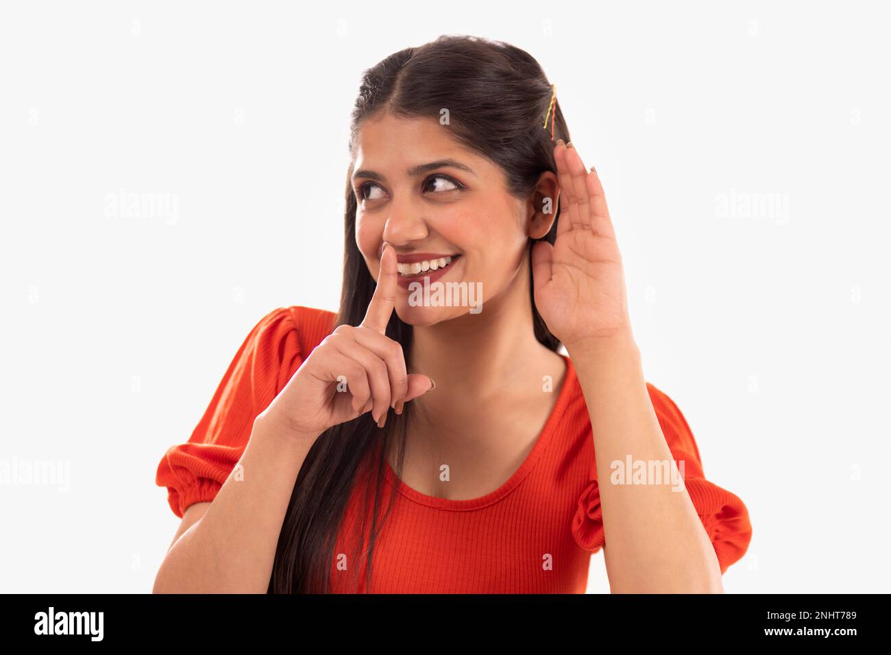 Portrait of beautiful woman showing hush gesture against white ...