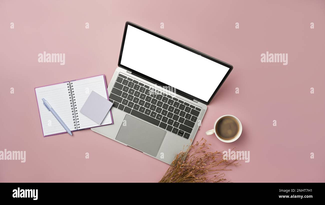 Above view of laptop computer, notepad and coffee cup on pink ...