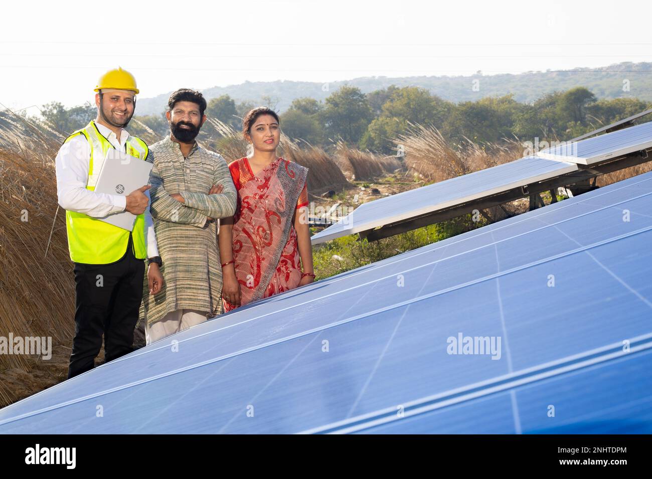Happy young indian couple and technician standing near solar panels ...