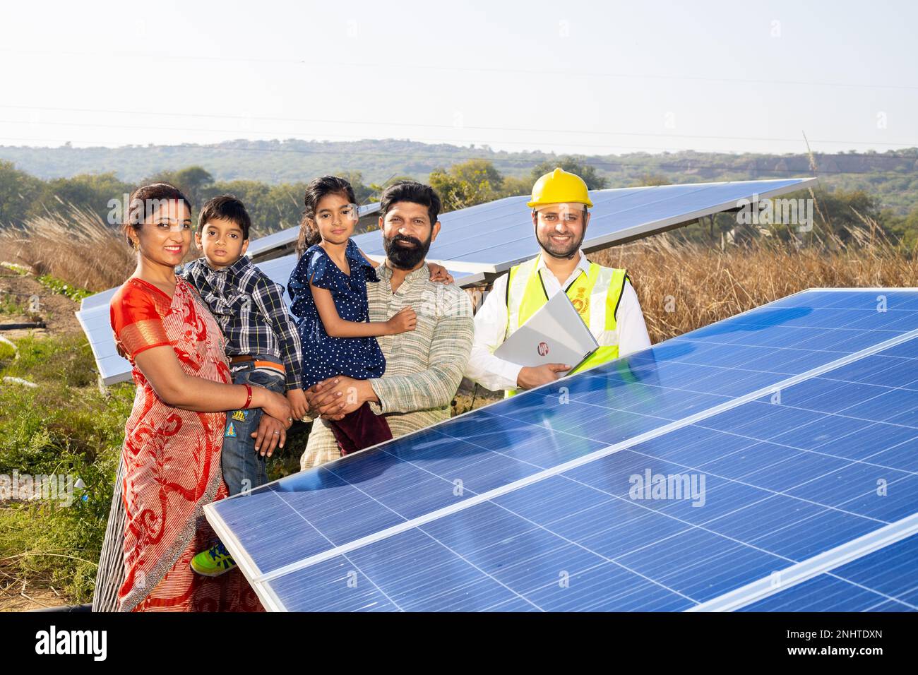 Happy young indian family and technician standing near solar panels ...