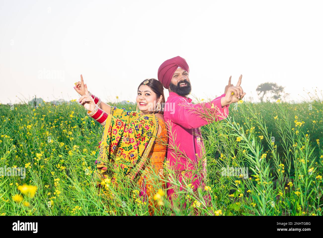 Happy Punjabi sikh couple doing bhangra dance in agriculture field ...