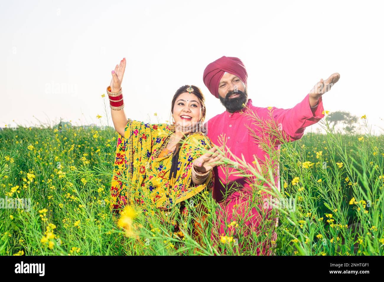 Cheerful Punjabi sikh couple doing bhangra dance in agriculture field ... Cheerful Punjabi sikh couple doing bhangra dance in agriculture field ...