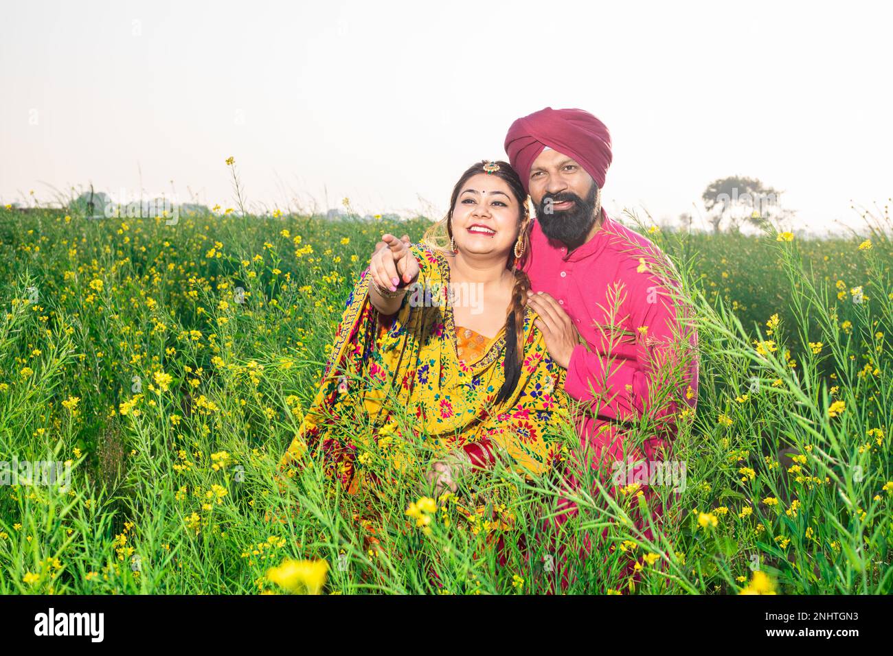 Happy young Punjabi sikh couple standing together at agriculture field ...