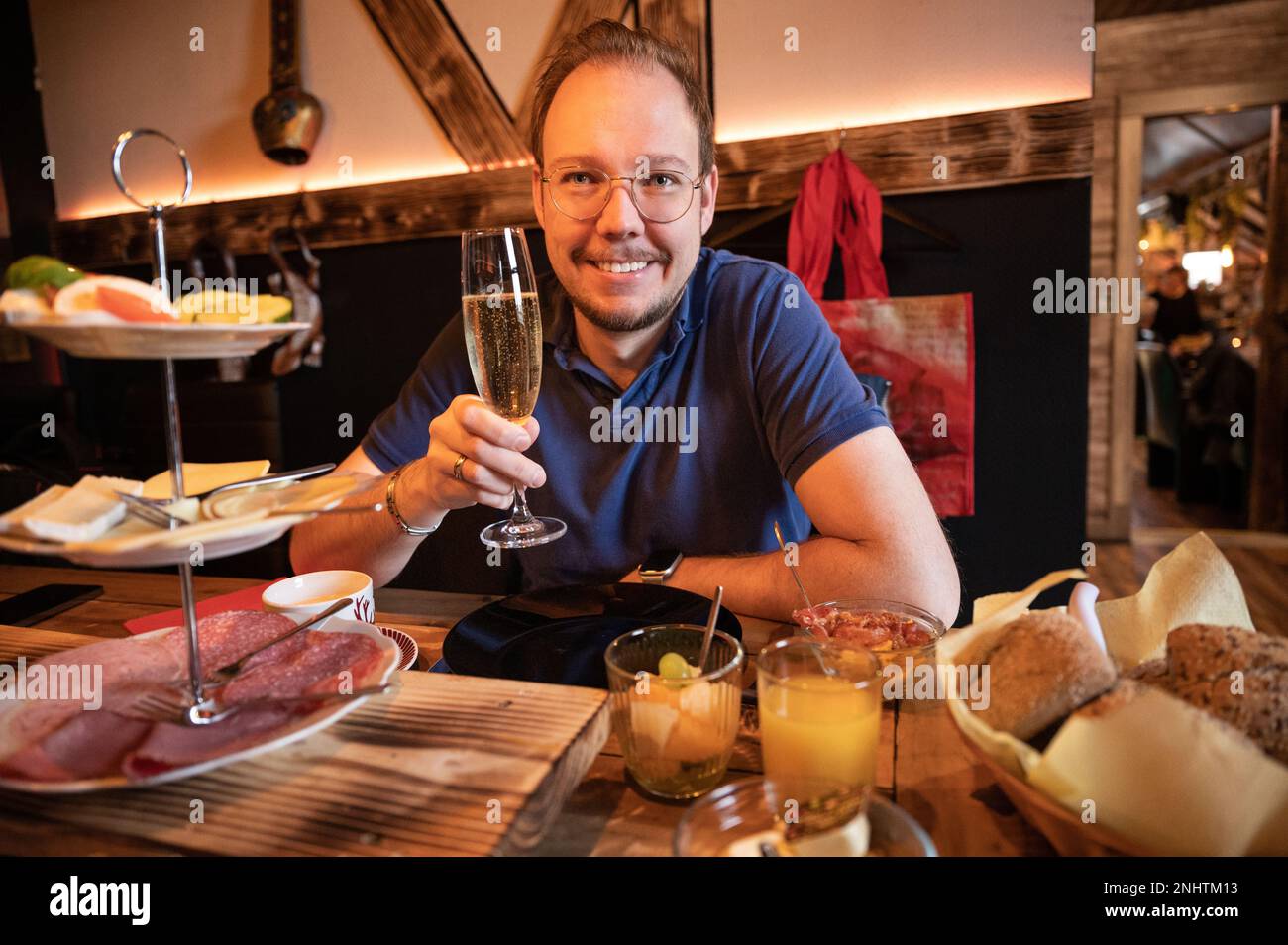 Smiling man drinking a glass of prosecco while sitting at a decorated ...