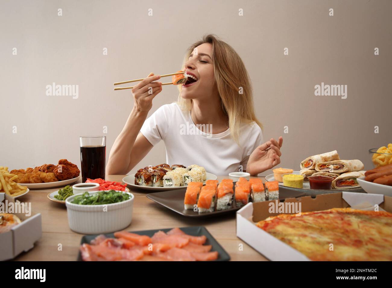 Food blogger eating at table against beige background. Mukbang vlog ...