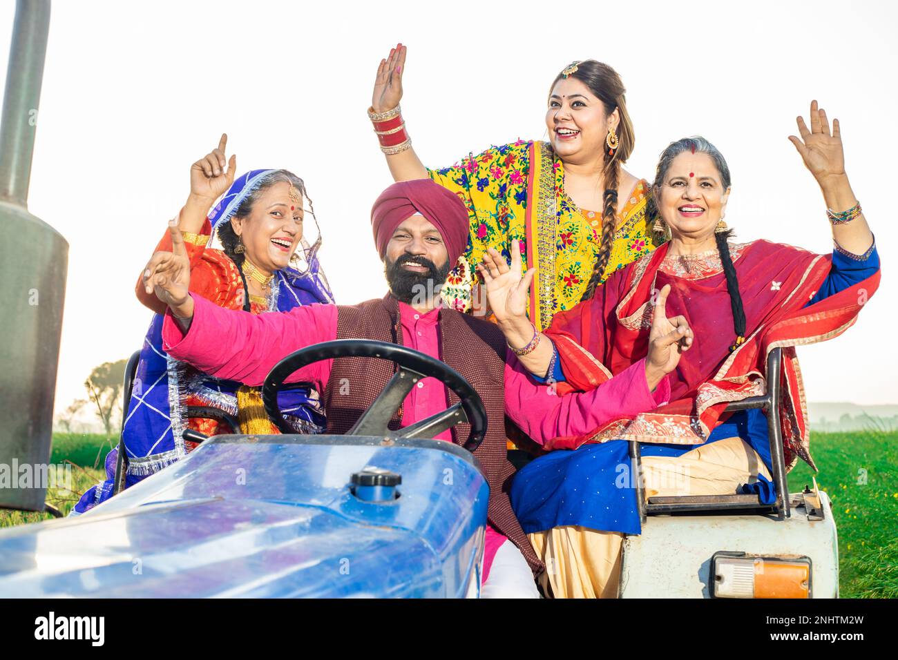 Happy punjabi sikh farmer family sitting on tractor dancing and ...