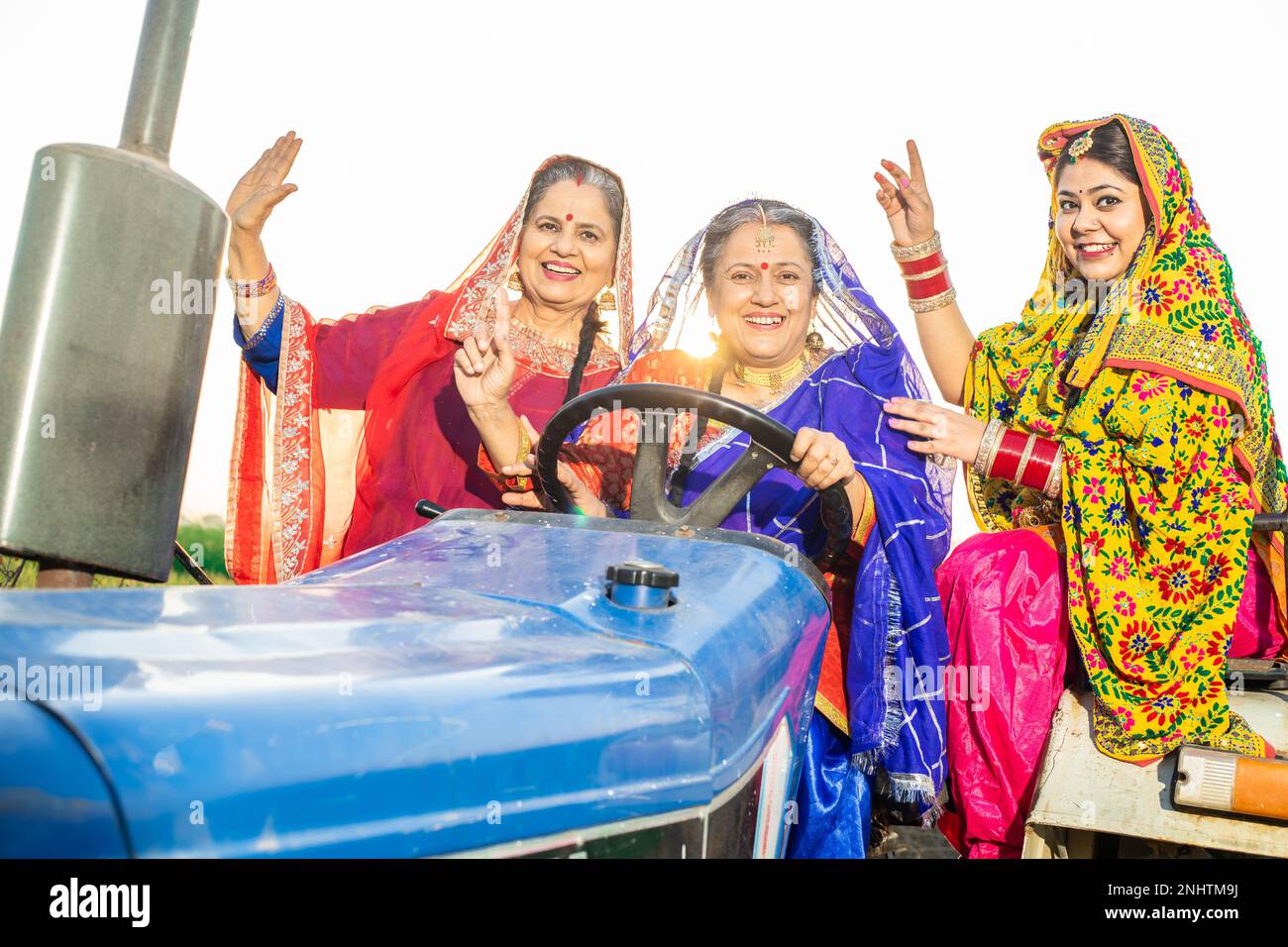 Group of happy punjab women driving tractor at agriculture field ...