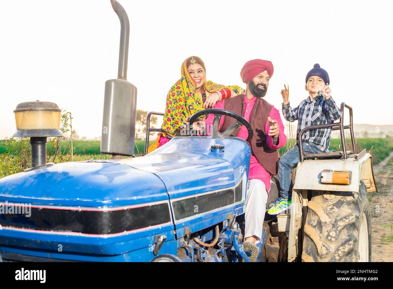 Happy young punjab farmer family sitting on tractor dancing and ...