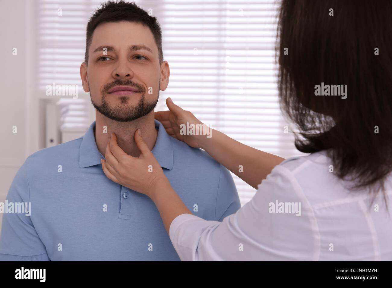 Doctor examining thyroid gland of patient indoors Stock Photo - Alamy
