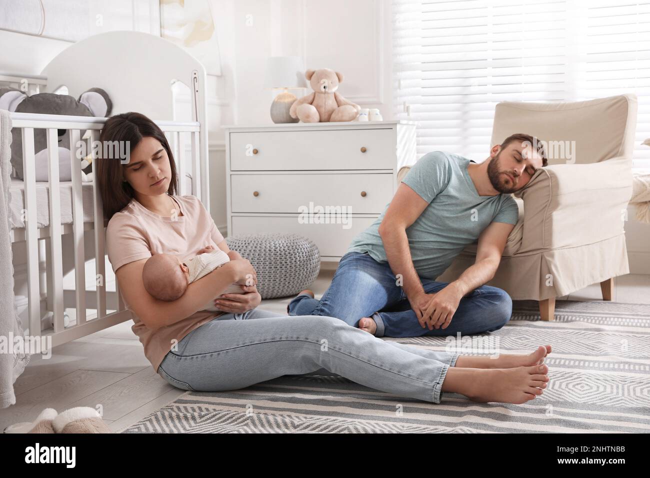Tired young parents with their baby sleeping on floor in children's ...