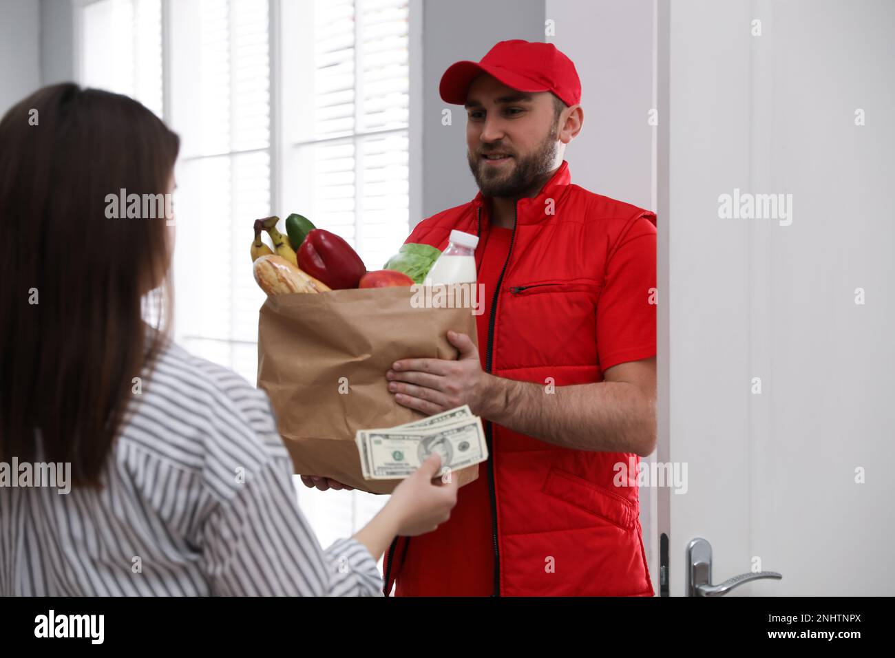 Young woman giving tips to courier indoors Stock Photo - Alamy