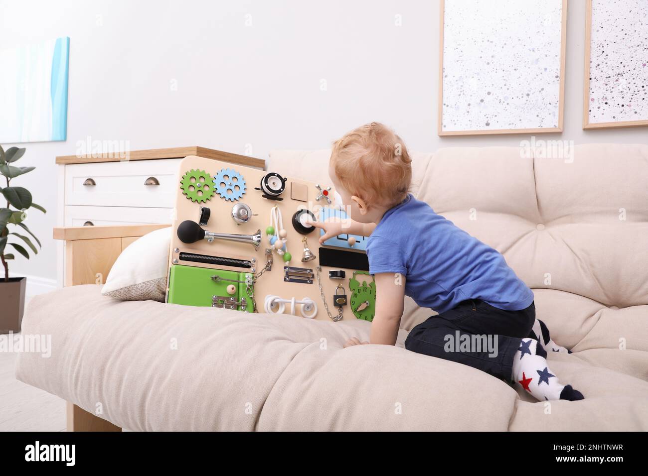 Cute little boy playing with busy board on sofa at home Stock Photo - Alamy