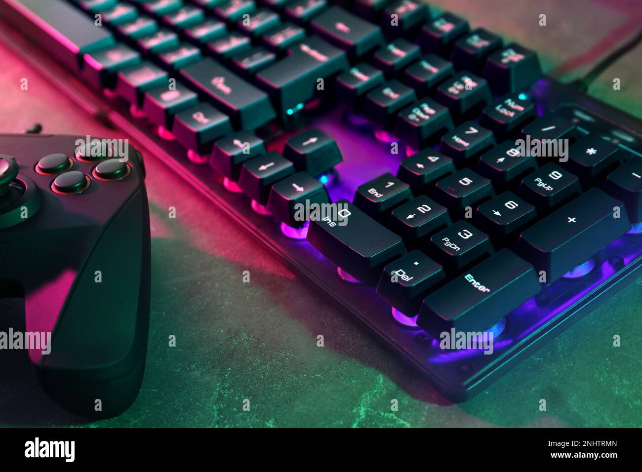Modern RGB keyboard and video game controller on grey table, closeup ...