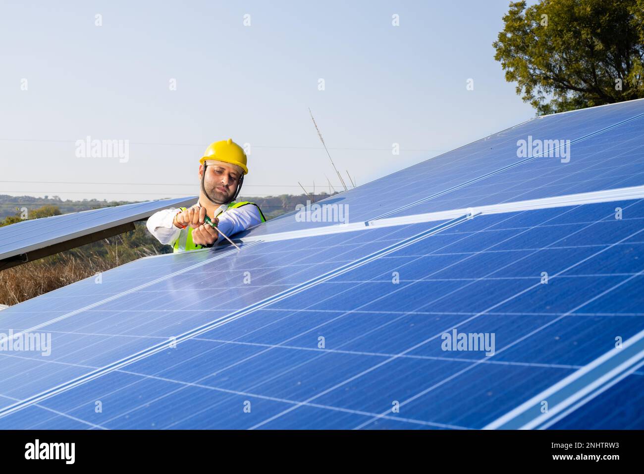 Young indian worker technician installing heavy solar panels outdoors ...