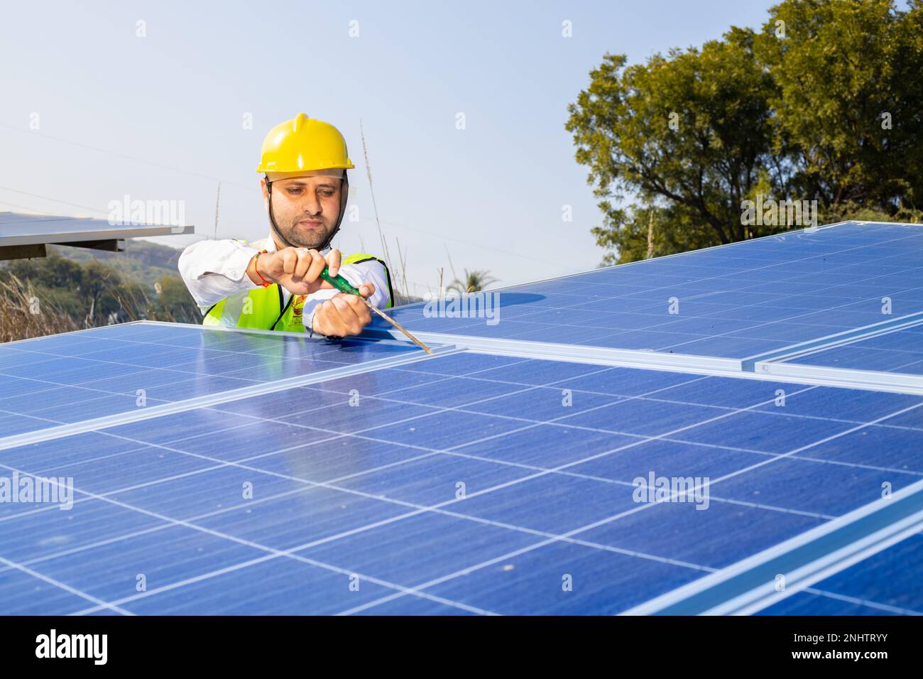 Young indian worker technician installing heavy solar panels outdoors ...