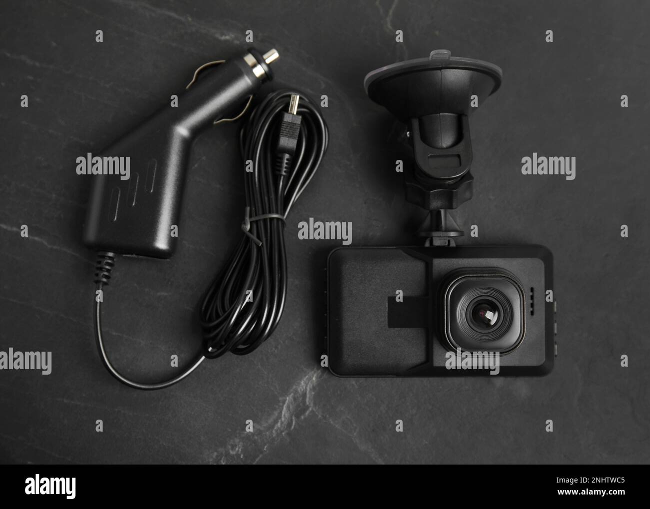 Modern car dashboard camera with suction mount and charger on black ...