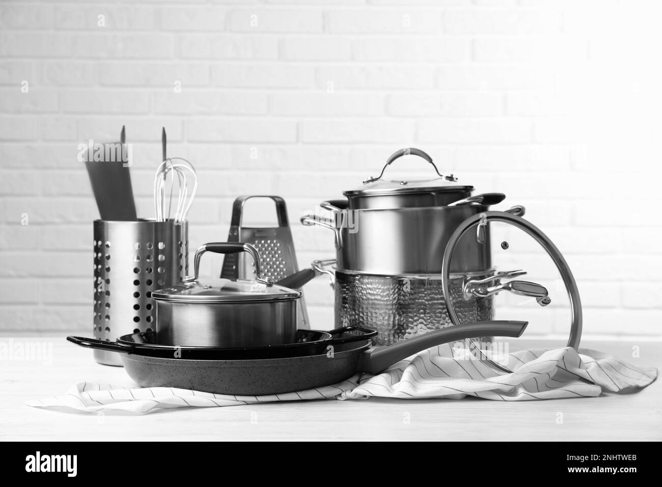 Set of clean kitchenware on white table against brick wall Stock Photo ...