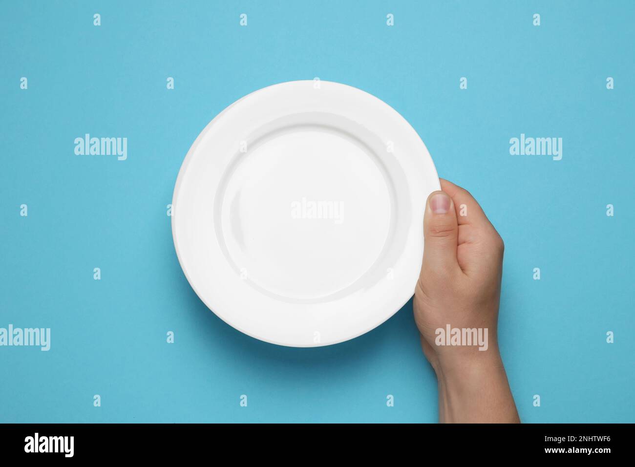 Top view of man holding empty plate on light blue background, closeup ...
