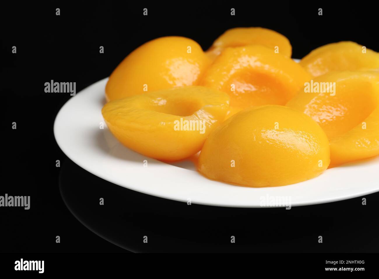 Plate with canned peach halves on black background, closeup Stock Photo ...