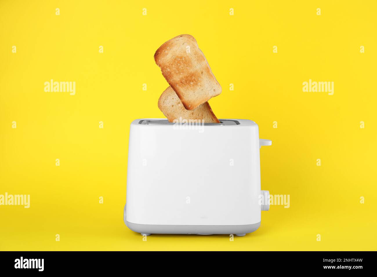 Bread slices popping up out of electric toaster on yellow background ...