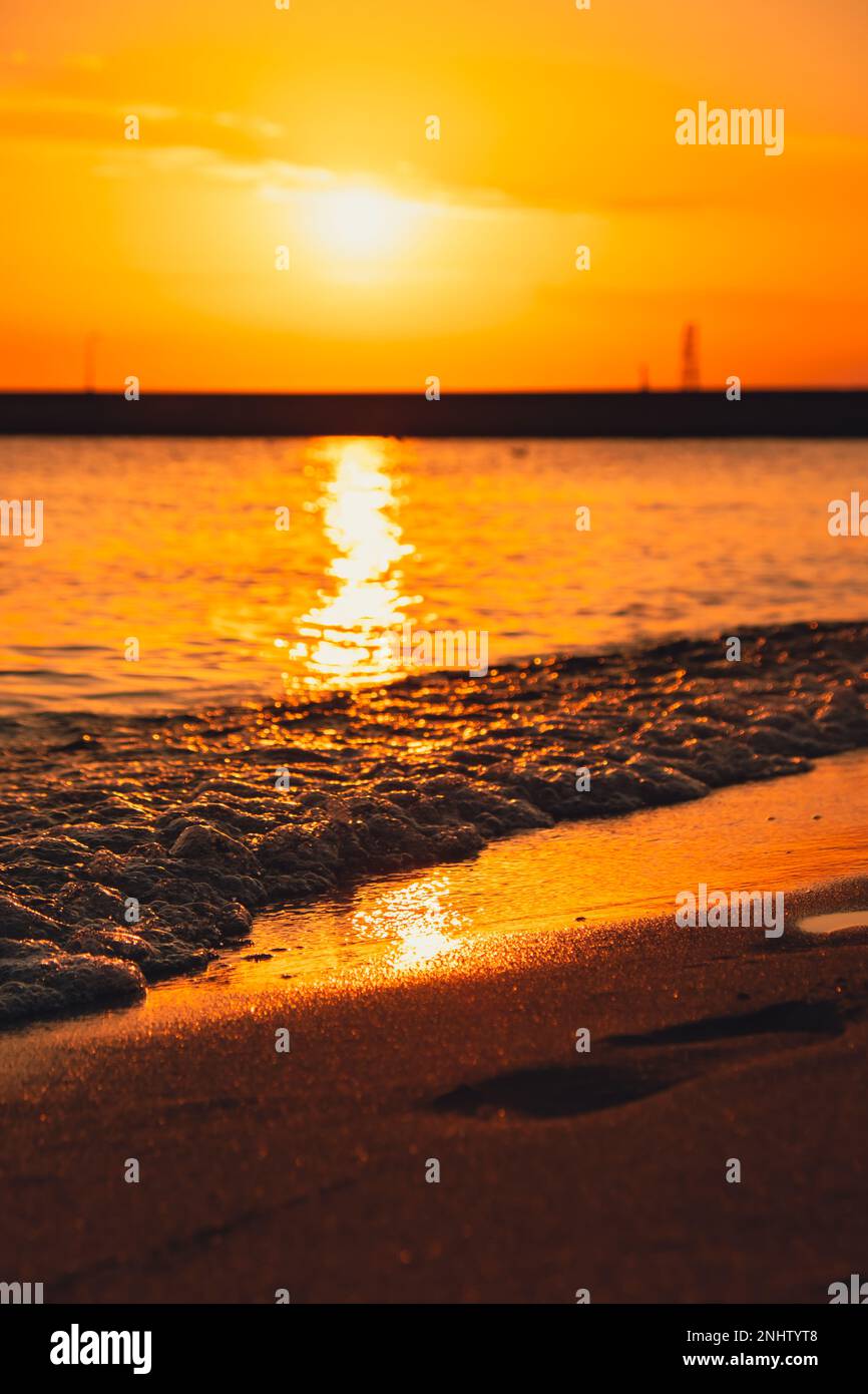 Reflection of sunlight over sea surface at sunset. Orange and gold blue ...