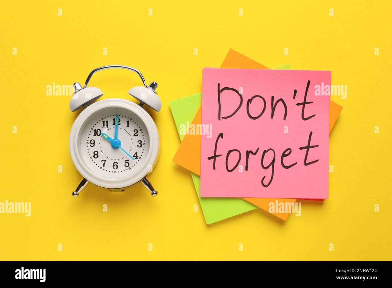 Alarm clock and reminder notes with phrase Don't forget on yellow ...