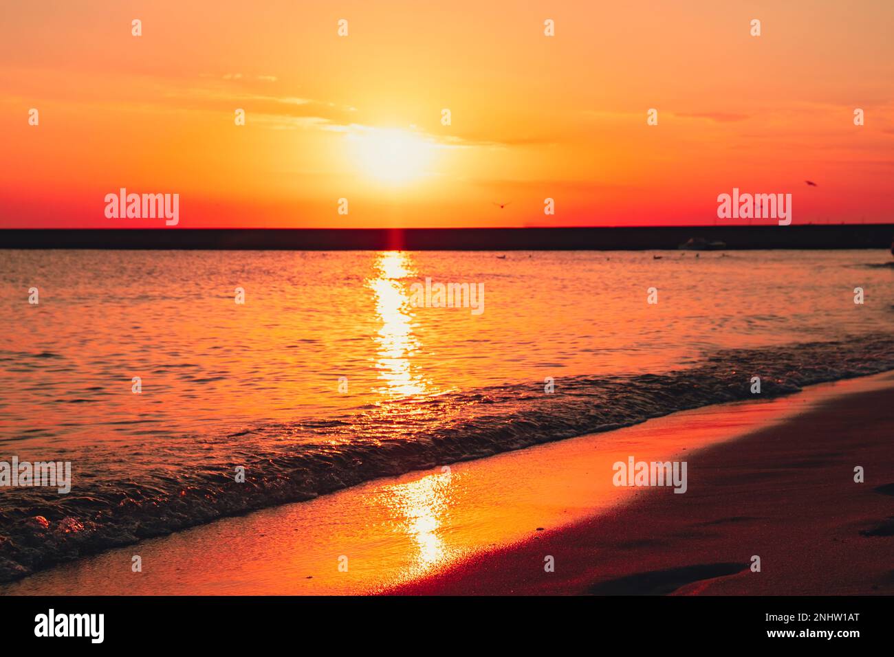 Reflection of sunlight over sea surface at sunset. Orange and gold blue ...