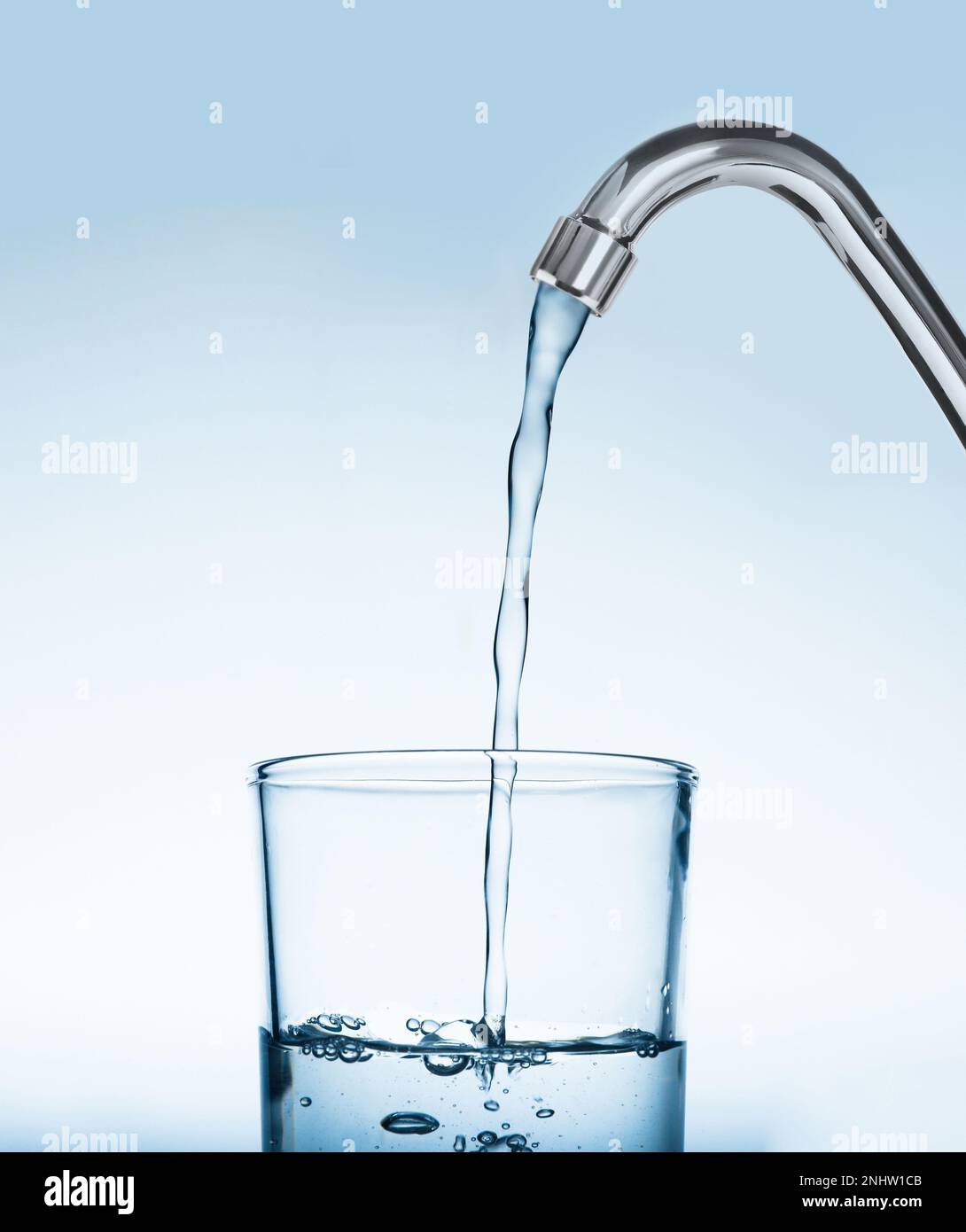 Filling glass with water from tap on light blue background Stock Photo ...