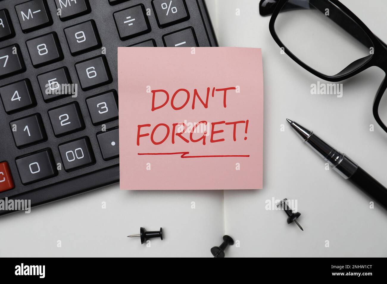 Reminder note with text DON'T FORGET, calculator and pen on open ...